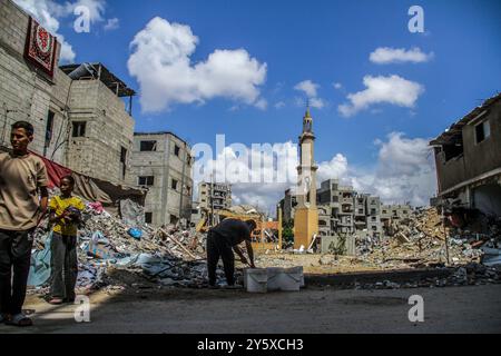 Palestinians walk amid buildings destroyed by Israeli air and ground ...