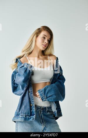 Blonde woman displays her trendy denim look and handbag in studio Stock ...
