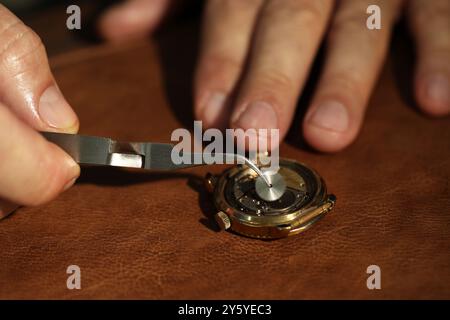 Man fixing mechanism of vintage wrist watch at wooden table, closeup ...