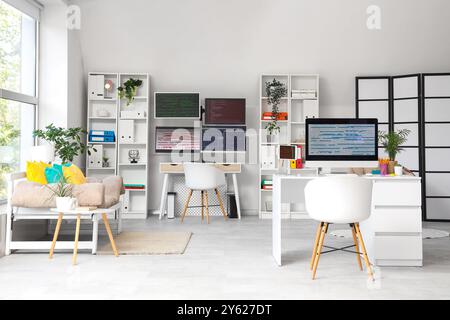 Interior of light programmer's office with desks, shelf units and sofa ...