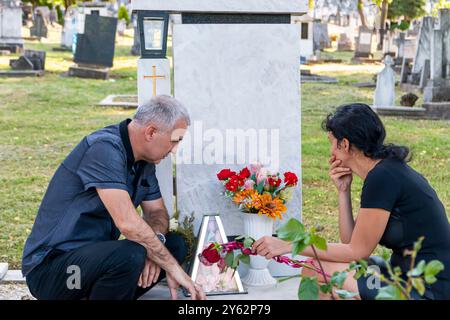 Mature couple in grief, in black clothes, holding a flower and mourning ...