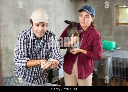 Woman and man holding rabbit and feed in their hands Stock Photo - Alamy