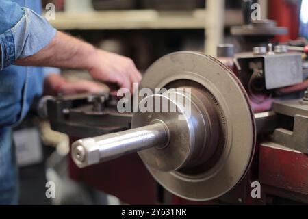 Mechanic adjusts lathe to grind brake disc Stock Photo - Alamy