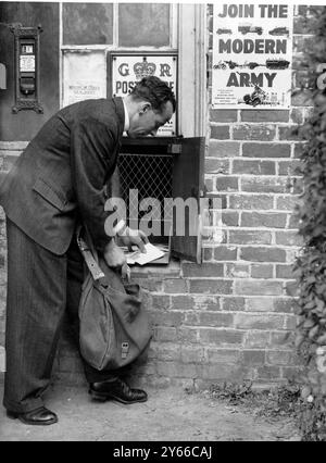 Postman collecting mail from Postbox, ready to load into Postvan Stock ...