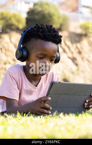 African american boy wearing headphones at home watching basketball ...