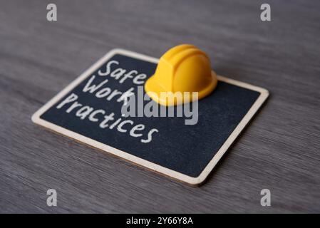 Small chalkboard with the text “Safe Work Practices” and yellow hard ...