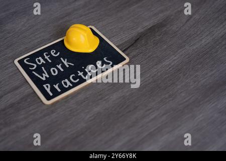 Small chalkboard with the text “Safe Work Practices” and yellow hard ...