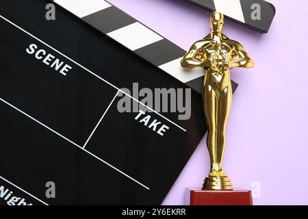 Golden Oscar award and movie clapper on violet background Stock Photo ...