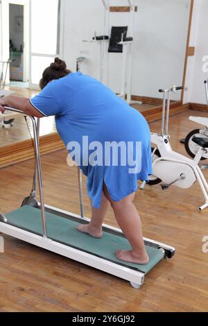 a woman with excess weight is running on a track in the park to lose ...
