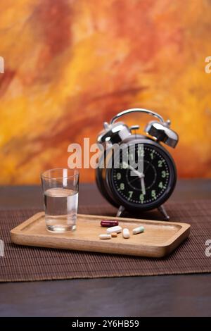 Clock with pills and glass of water on table in room, closeup Stock ...