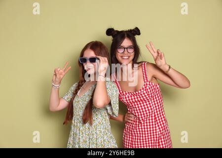 Happy teenage girls showing peace signs on green background Stock Photo ...
