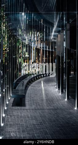A modern architectural pathway surrounded by greenery at night with ...