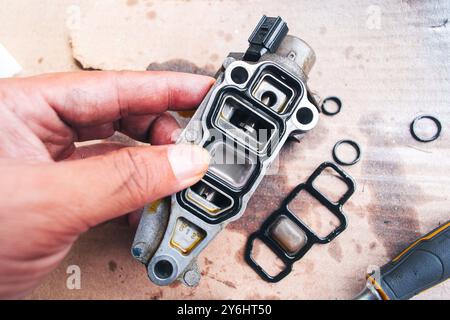 A mechanic is replacing a worn out rubber seal to repair a car engine ...