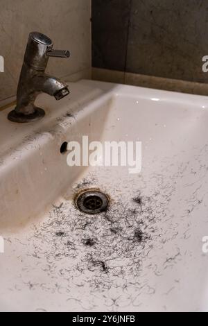 untidy ceramic sink covered with shaved hairs. Represents poor hygiene ...