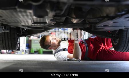 car mechanic in work clothes works in a workshop and repairs a vehicle ...