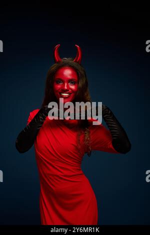 A striking woman in red with devil horns passionately celebrates ...