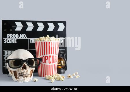 Human skull with 3D glasses, clapperboard, tasty popcorn and lantern ...