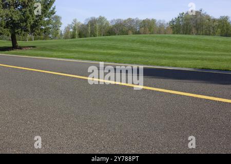 Asphalt road for cyclists and pedestrians through the green lawn in the ...