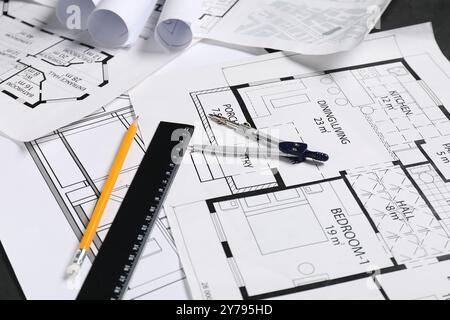 Different engineering drawings, ruler, divider and pencil on table ...