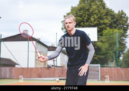 Badminton player strikes the shuttlecock during a game on an outdoor ...