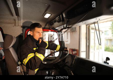 Firefighter using radio set while driving fire truck Stock Photo - Alamy