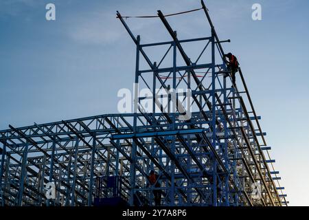 Workers working at height on clad rack structure installing steel ...