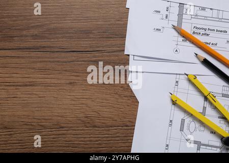 Different technical drawings, pencils and divider on wooden table, flat ...