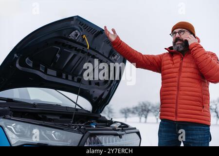 Angry man standing by electric car, battery run out of power before ...