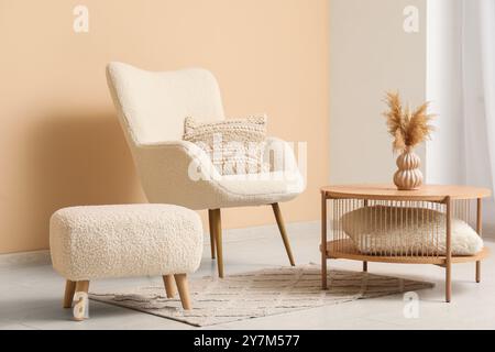 Comfortable armchair with soft pouf and table near white wall in living ...