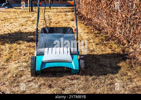 Electric lawn scarifier in spring garden during lawn maintenance with ...