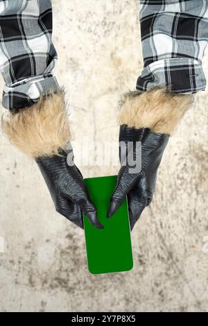 Werewolf hand with fur and black claws using a mobile phone or cell ...