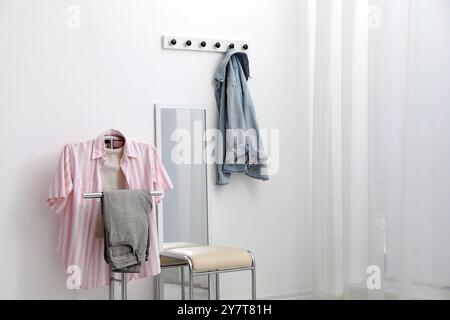 Coat rack, stool, mirror and clothes in hallway Stock Photo - Alamy