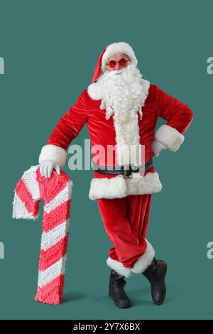 Santa Claus with candy cane pinata on green background Stock Photo - Alamy