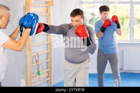 Man punching hits punch mitts is training with coach in box gym Stock ...