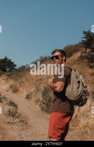 Confident male adventurer with backpack walking by the mountain ...