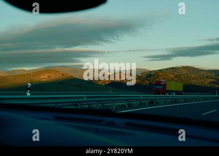 View through car windshield of mountain road between the trees on sunny ...