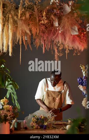 Young delivery man with bouquet of beautiful flowers on yellow ...