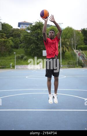Vertical photo of a basketball player throwing a ball in an outdoor ...