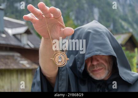 An old monk with a beard holds an hourglass amulet in his hand Stock ...