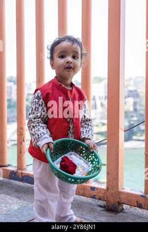isolated cute kid devotee with holy offering at temple in indian ...