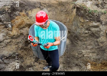 Workers install concrete septic tank into trench at construction site ...