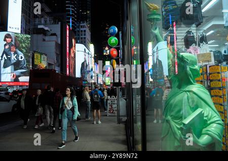 People walk past a model of the Statue of Liberty outside of a store in ...