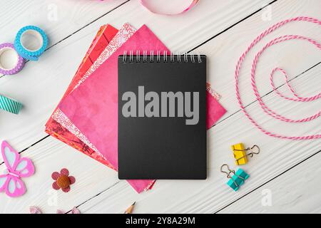 Crafting essentials on a workspace featuring a black notebook, colorful ...