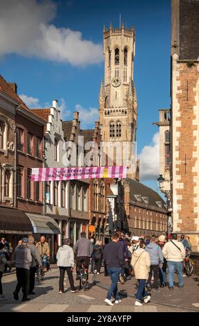 The Belfry of Bruges towers above an old rooftop, framed by a blue sky ...