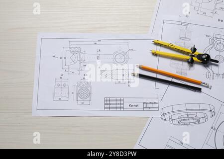 Different engineering drawings, pencils and divider on wooden table ...