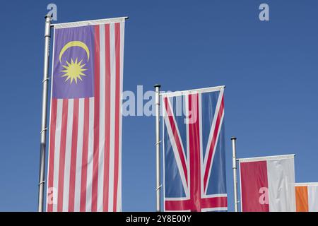Several flags of different countries fly side by side under a clear ...