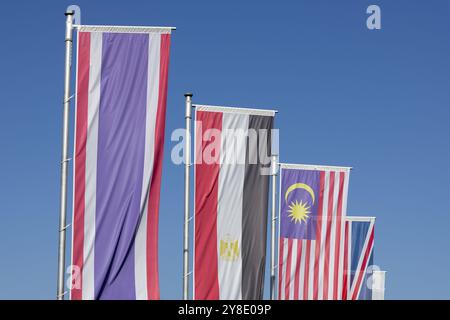 Several flags of different countries fly side by side under a clear ...