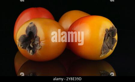 Red ripe persimmons rotating over black background Stock Photo - Alamy