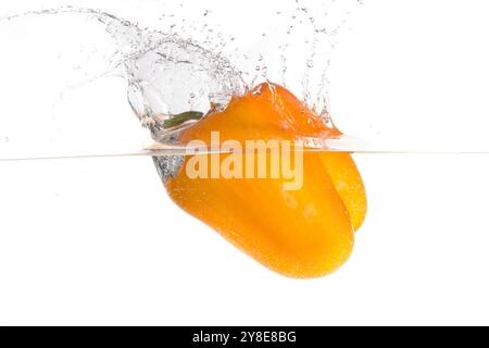 A large orange bell pepper making a splash after being dropped in water ...