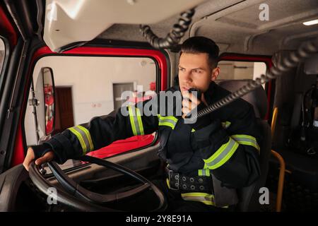 Firefighter using radio set while driving fire truck Stock Photo - Alamy